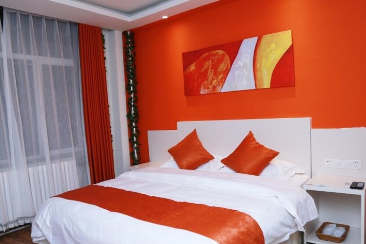 Quarto de hotel com cama, mesa de cabeceira e uma obra de arte na parede.