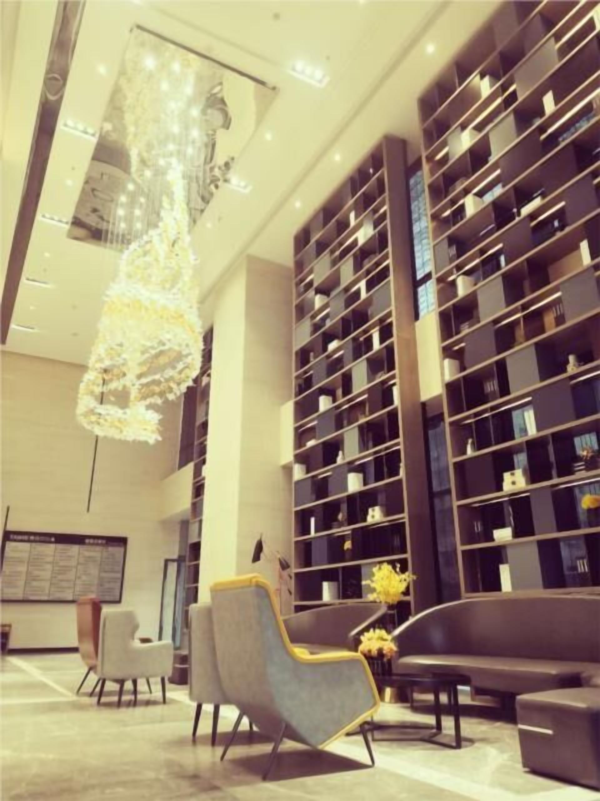 Um interior moderno com uma grande estante, um candelabro e mobiliário contemporâneo.