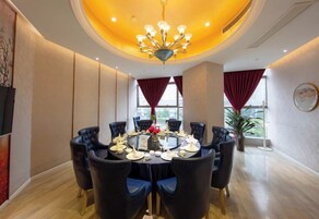 Mesa de jantar redonda com cadeiras, um lustre e uma janela com cortinas.