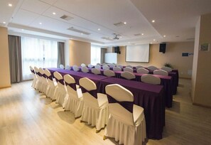 Sala de conferências com uma mesa comprida, cadeiras, tela de projetor e quadro branco.