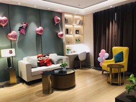 Uma sala de estar moderna com sofá, uma poltrona amarela, uma mesa de centro redonda e balões decorativos em formato de coração.