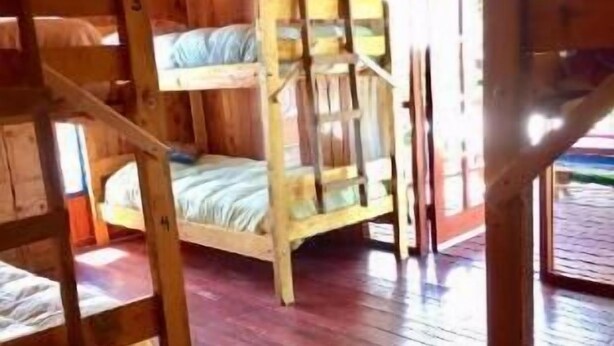 Uma cabana de madeira com beliches, escada e piso de madeira.