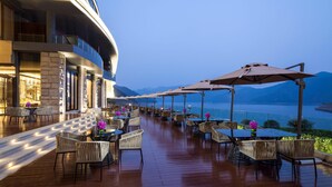 Restaurante à beira-mar com área externa, mesas, cadeiras e guarda-sóis.