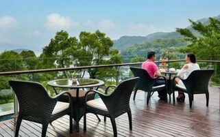 Um casal jantando à mesa com vista para uma paisagem montanhosa.