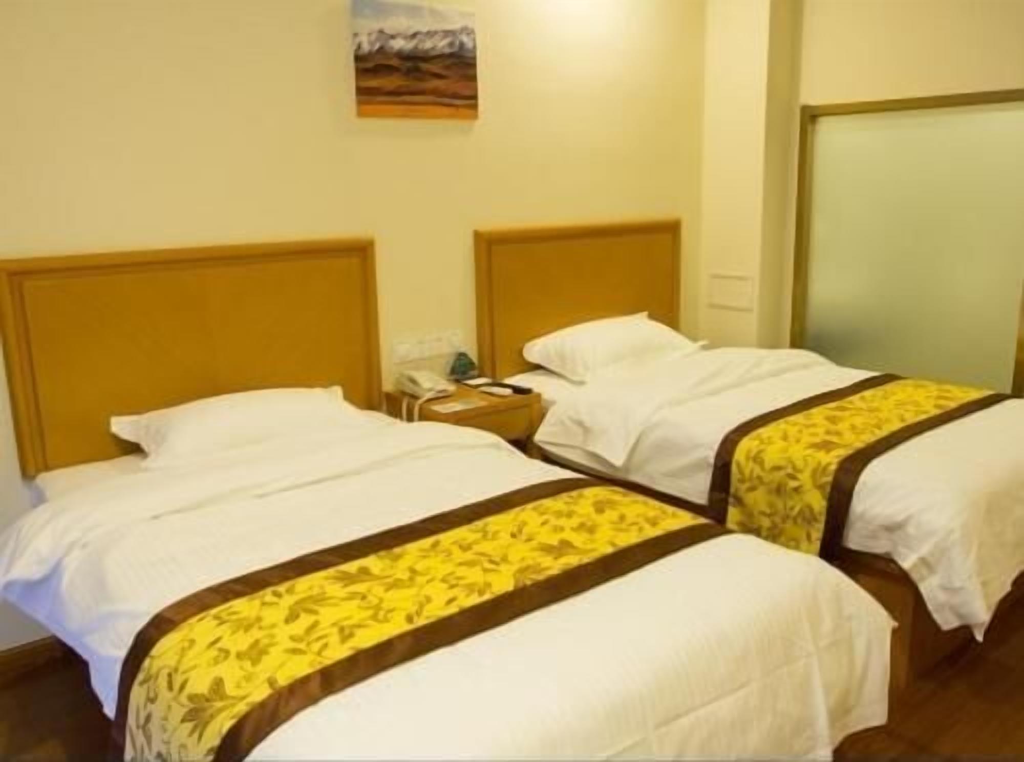 Quarto de hotel com duas camas, cabeceiras de madeira, mesa de cabeceira com telefone e um quadro na parede.