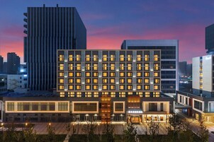 Um hotel moderno com disposição em grade, entrada central e um pátio interno.