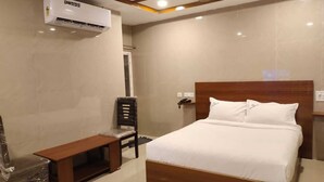 Quarto de hotel com cama, mesa de cabeceira, cadeira e ar condicionado.
