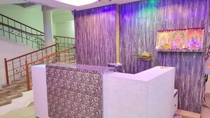 Um balcão de recepção com estofamento estampado, uma escadaria com corrimãos de metal e uma parede com acabamento texturizado.