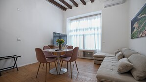 Uma sala de estar moderna com área de jantar, piso de madeira, um sofá e um quadro na parede.