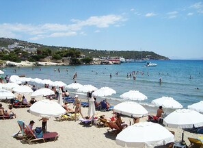 Uma praia com guarda-sóis e pessoas tomando sol.