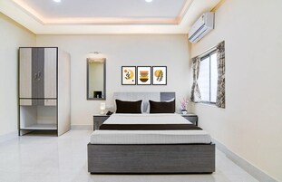 Quarto moderno com cama, guarda-roupa, mesa de cabeceira, espelho e obras de arte na parede.