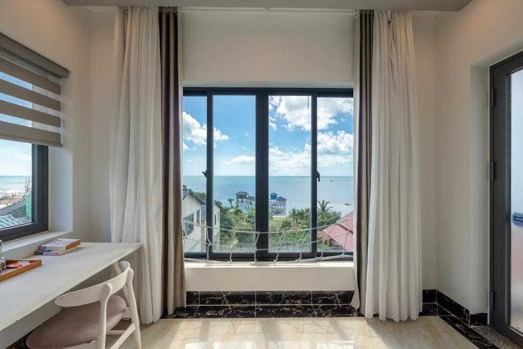 Um quarto com uma janela grande, uma escrivaninha e uma cadeira.