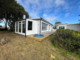 Uma casa moderna com um deck espaçoso, piscina e área de jardim.