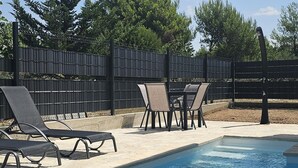 Uma piscina com espreguiçadeiras e uma cerca.