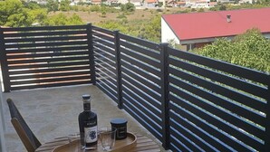 Uma varanda com uma mesa, cadeiras e uma garrafa de bebida alcoólica.