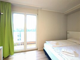 Quarto com cama, porta de correr de vidro e vista para o exterior.