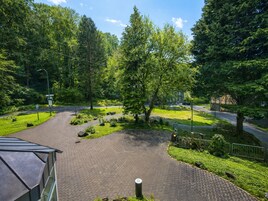 Um caminho pavimentado leva a um edifício de design moderno, cercado por vegetação exuberante e árvores.