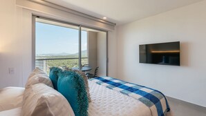 Quarto com cama, televisão, varanda e vista, além de uma janela.