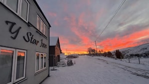 Um edifício chamado 'Star Inn', com paisagem coberta de neve e céu ao pôr do sol.
