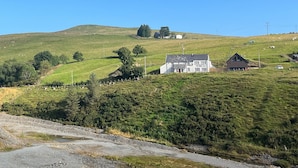 Paisagem rural com uma colina, um edifício branco com a placa 'Y Star Inn' e um edifício menor e escuro.