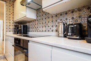 Uma cozinha com painel decorativo atrás do fogão, fogão, cafeteira e chaleira.