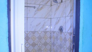 Chuveiro com parede de azulejos estampados, um chuveiro e um ralo.