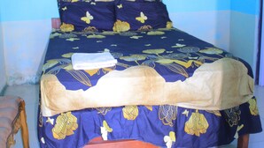 Uma cama com roupa de cama florida, cabeceira de madeira e chão de azulejos.