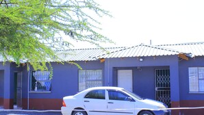 Um carro branco estacionado em frente a um edifício com telhado de chapa metálica e porta com grades de metal.