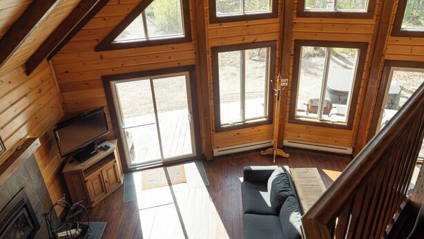 Um quarto estilo loft com interior em madeira, janelas amplas, lareira e escada.