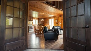 Um interior em madeira com área de jantar, cozinha e espaço para sentar.
