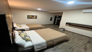 Quarto de hotel com duas camas, uma televisão, um quadro na parede e um aparelho de ar condicionado.