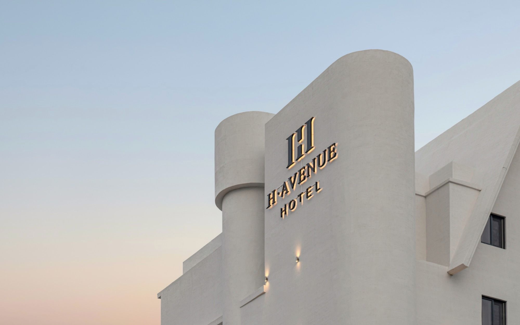 Exterior do Hotel Havenue, destacando sua arquitetura moderna e sinalização iluminada.