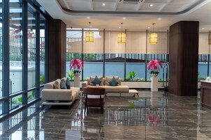 Um lobby moderno com área de estar, janelas amplas e plantas decorativas.