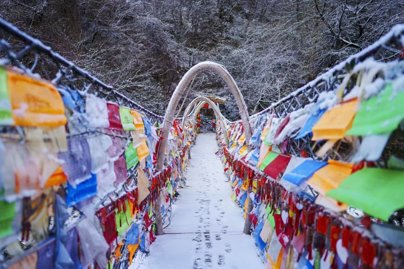Uma ponte coberta de neve com vibrantes bandeiras de oração.