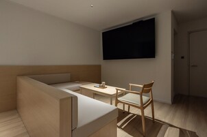 Quarto minimalista com sofá, mesa e cadeira.