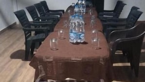 Uma mesa de jantar com cadeiras, garrafas de água e copos.