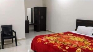 Quarto com cama, guarda-roupa e duas cadeiras.