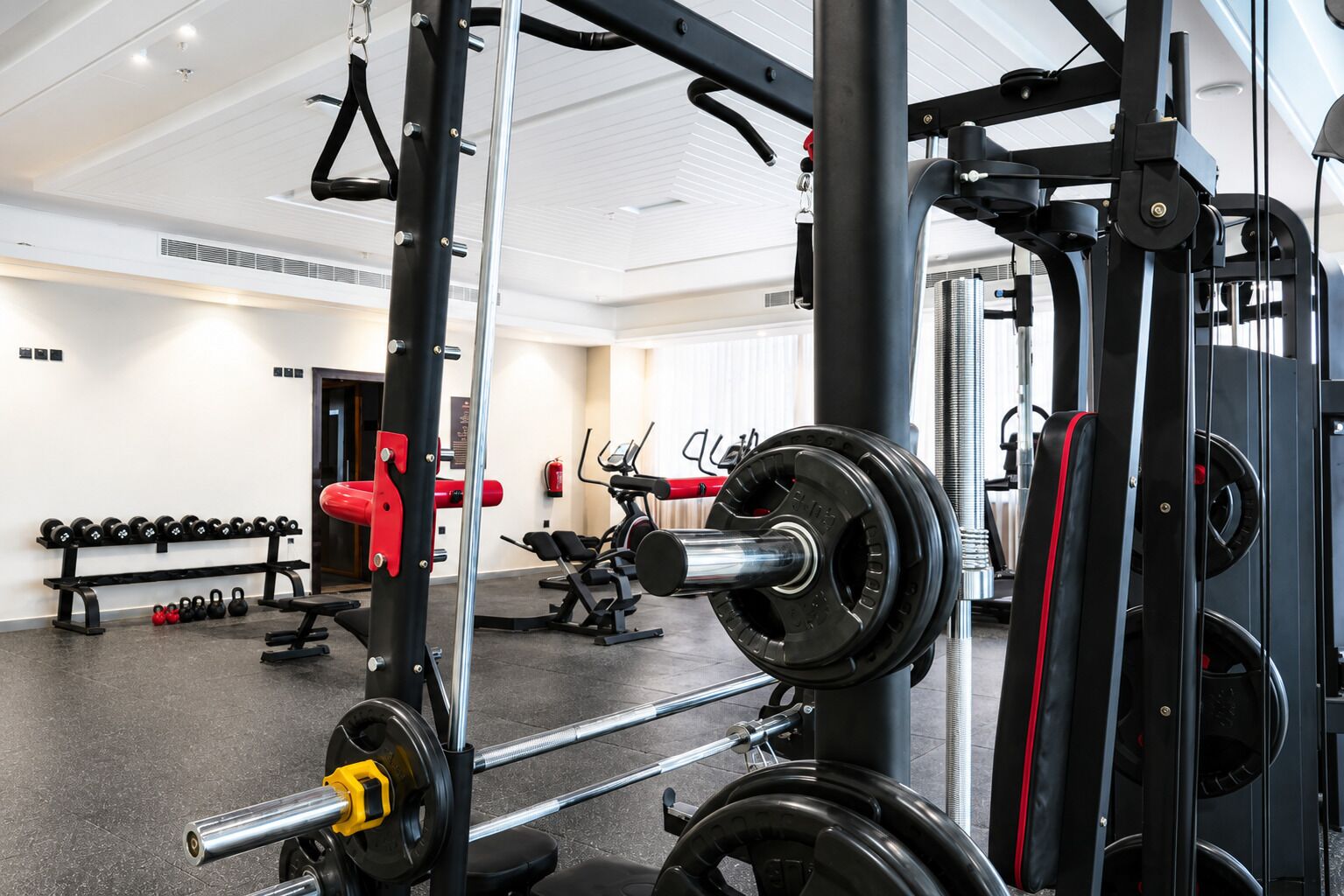 Uma academia com equipamentos de musculação, halteres e máquinas de cardio.