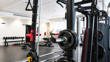 Uma academia com equipamentos de musculação, halteres e máquinas de cardio.