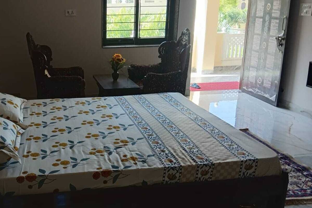 Um quarto com uma cama, uma mesinha com um vaso e uma cadeira.
