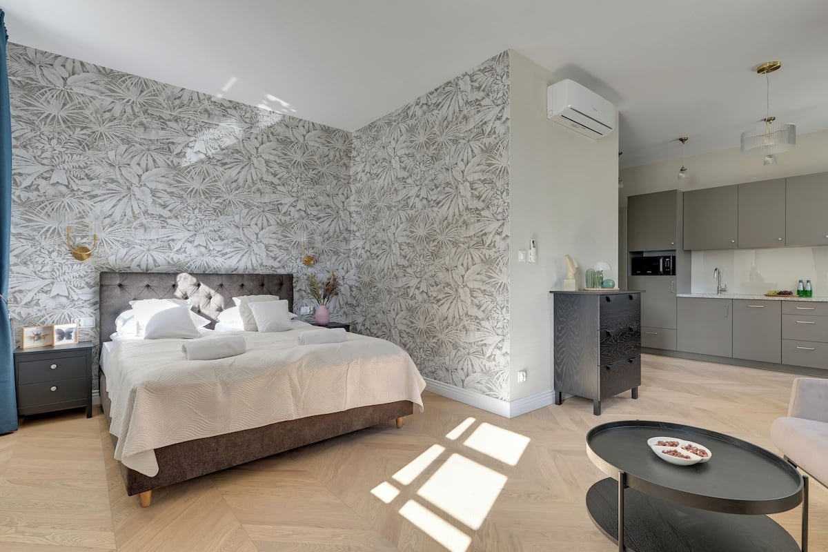 Quarto com cama, mesas de cabeceira, cômoda e um espaço de refeições com mesa e cadeiras.