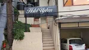 Um letreiro de hotel, uma escadaria e um carro estacionado.