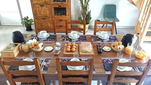 Mesa de jantar posta com cadeiras, um armário e diversos alimentos.