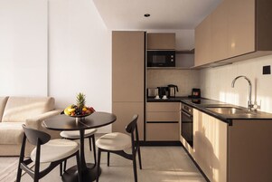 Uma cozinha moderna com área de jantar, incluindo uma mesa com cadeiras, micro-ondas, cafeteira e pia.