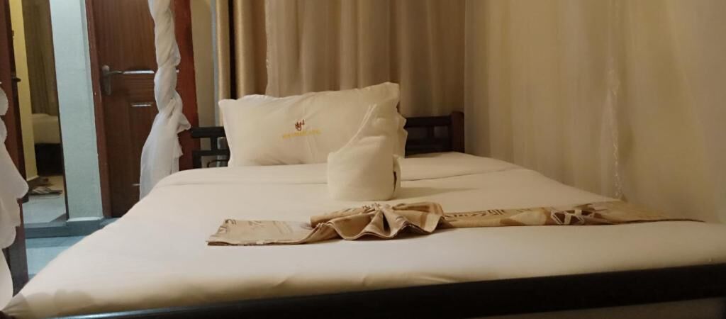 Cama bem arrumada com travesseiros e toalha dobrada.