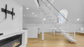 Um interior moderno com lareira, escadaria branca e área de jantar.