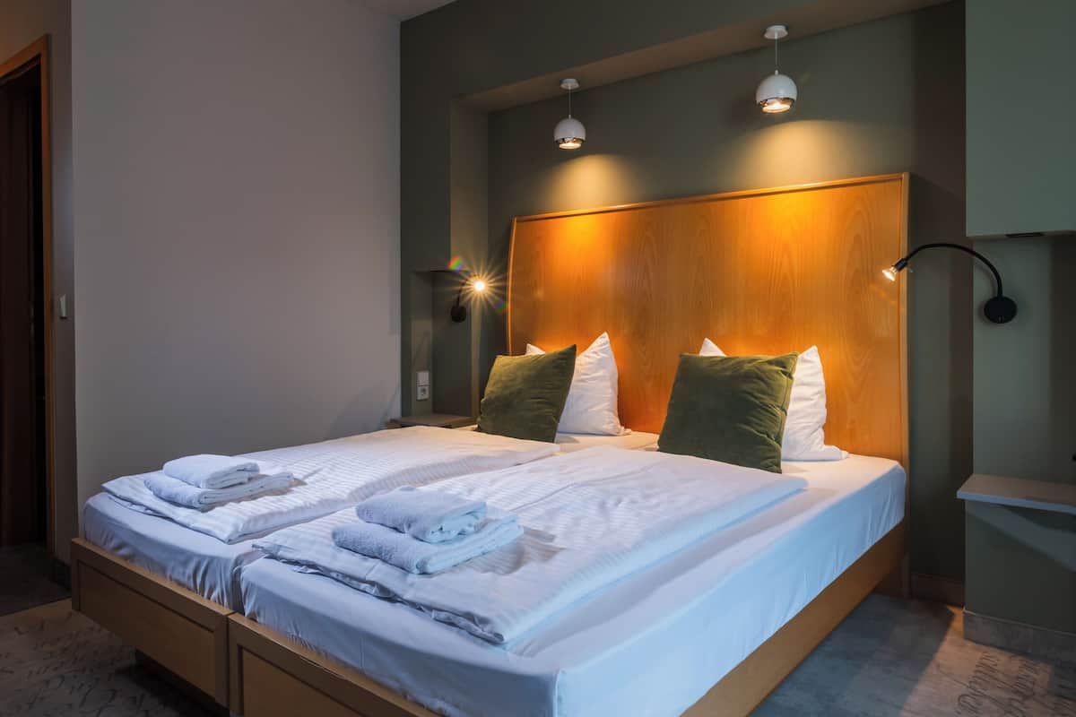 Quarto moderno com uma cama grande, abajures e um lustre diferenciado.