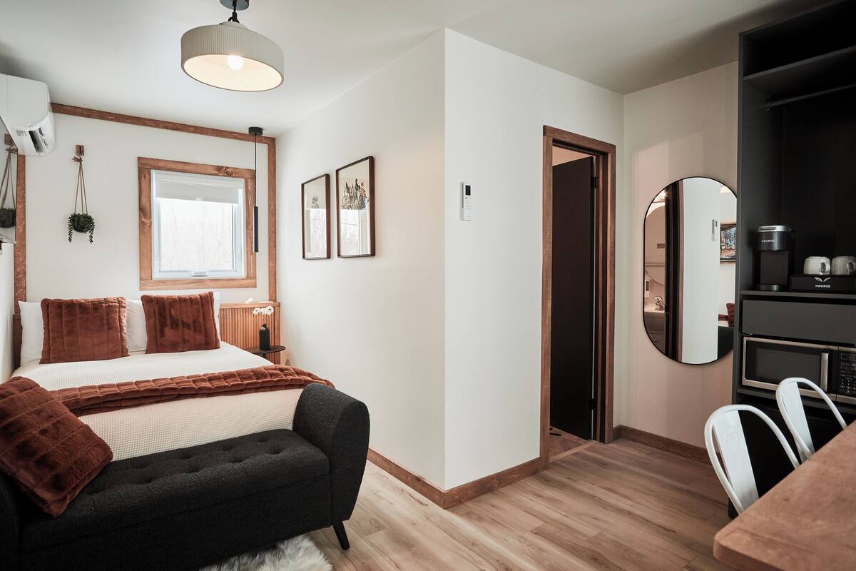 Quarto moderno com cama, mesa de cabeceira e um espelho grande.