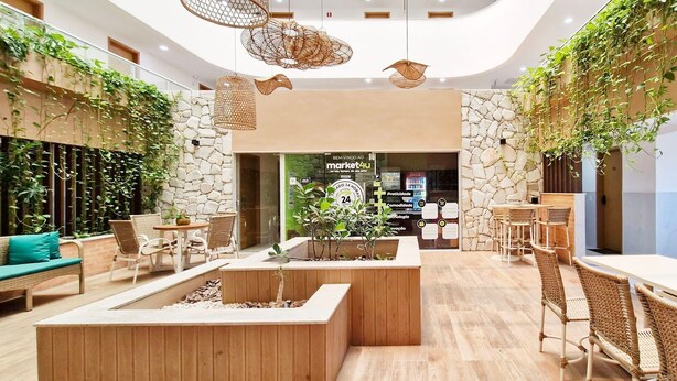 Um espaço interno moderno com área de estar central, paredes de pedra e plantas penduradas.