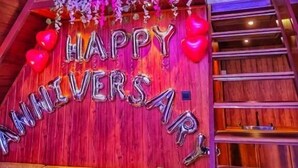 Interior de madeira com um letreiro de 'FELIZ ANIVERSÁRIO', um sofá e uma escada.